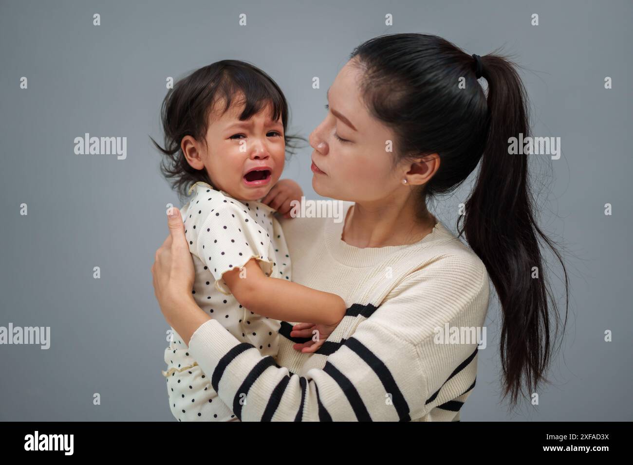 mother holding and comforting her crying toddler baby Stock Photo - Alamy