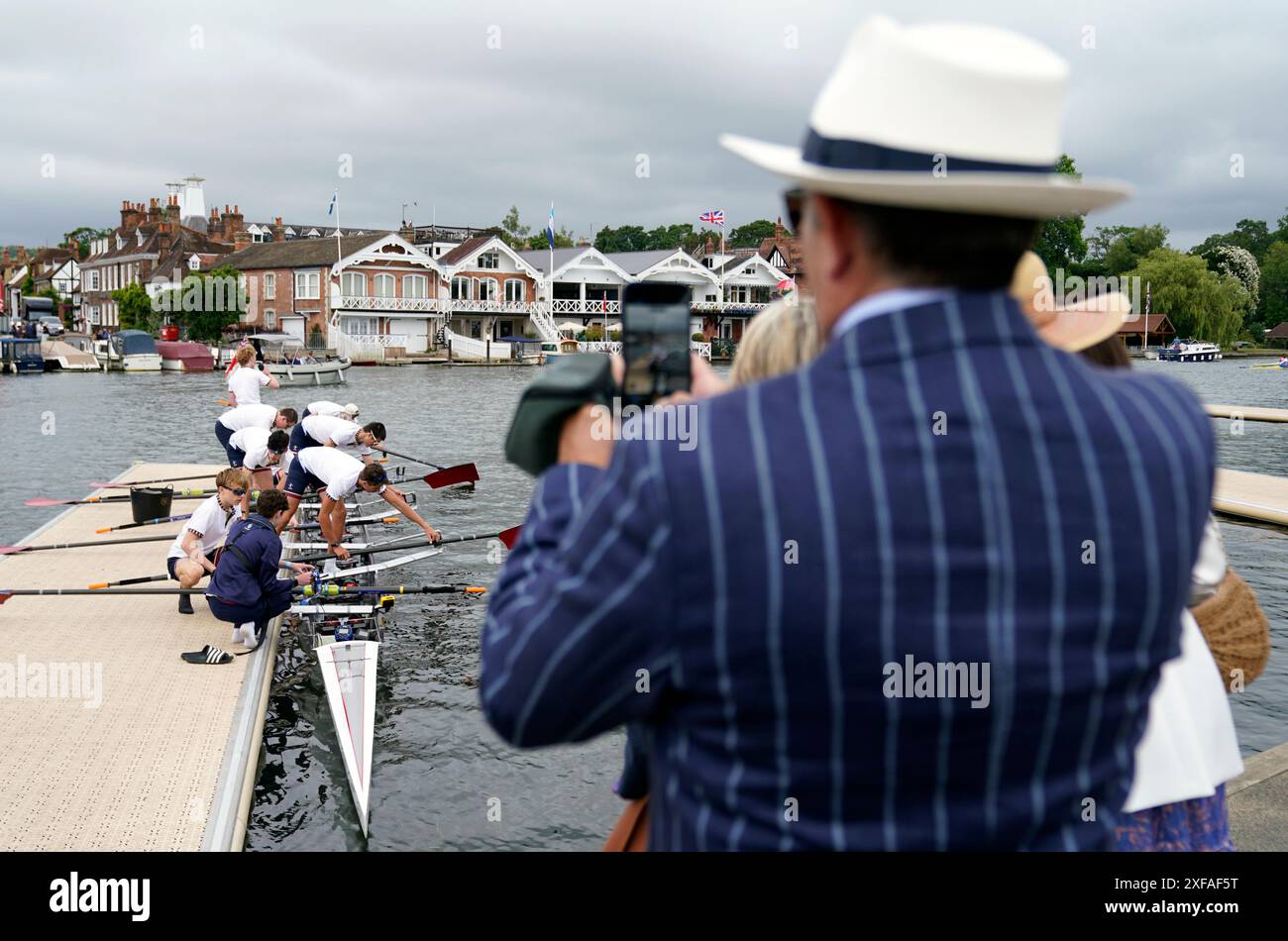 People look out from the side of the river as a rowing crew make their ...
