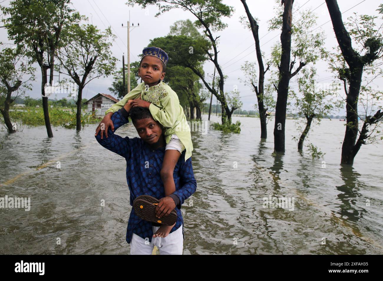 A Father carrying his son on his shoulder wades through floodwaters in ...