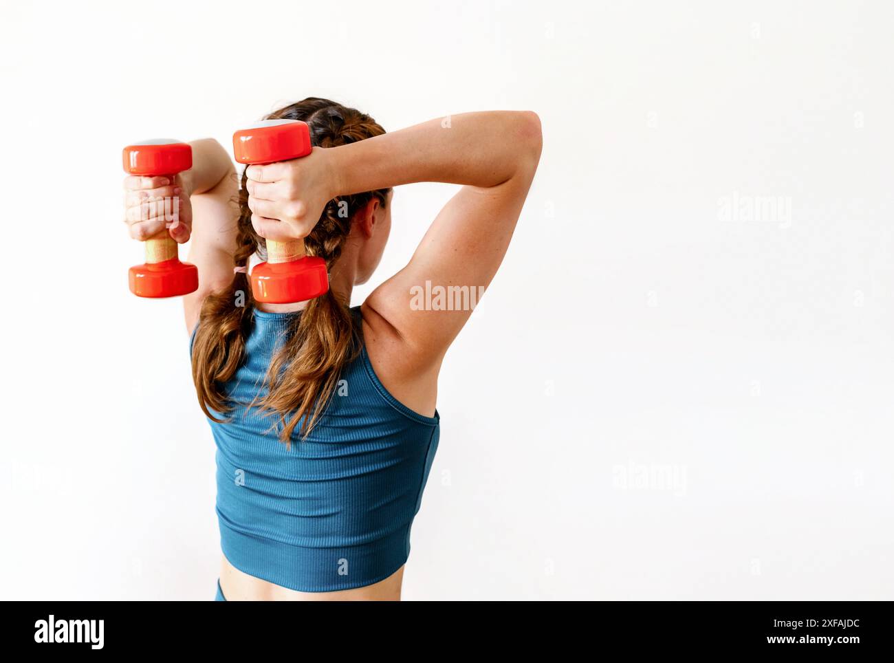 Rear view of female athlete doing triceps extension exercise with ...