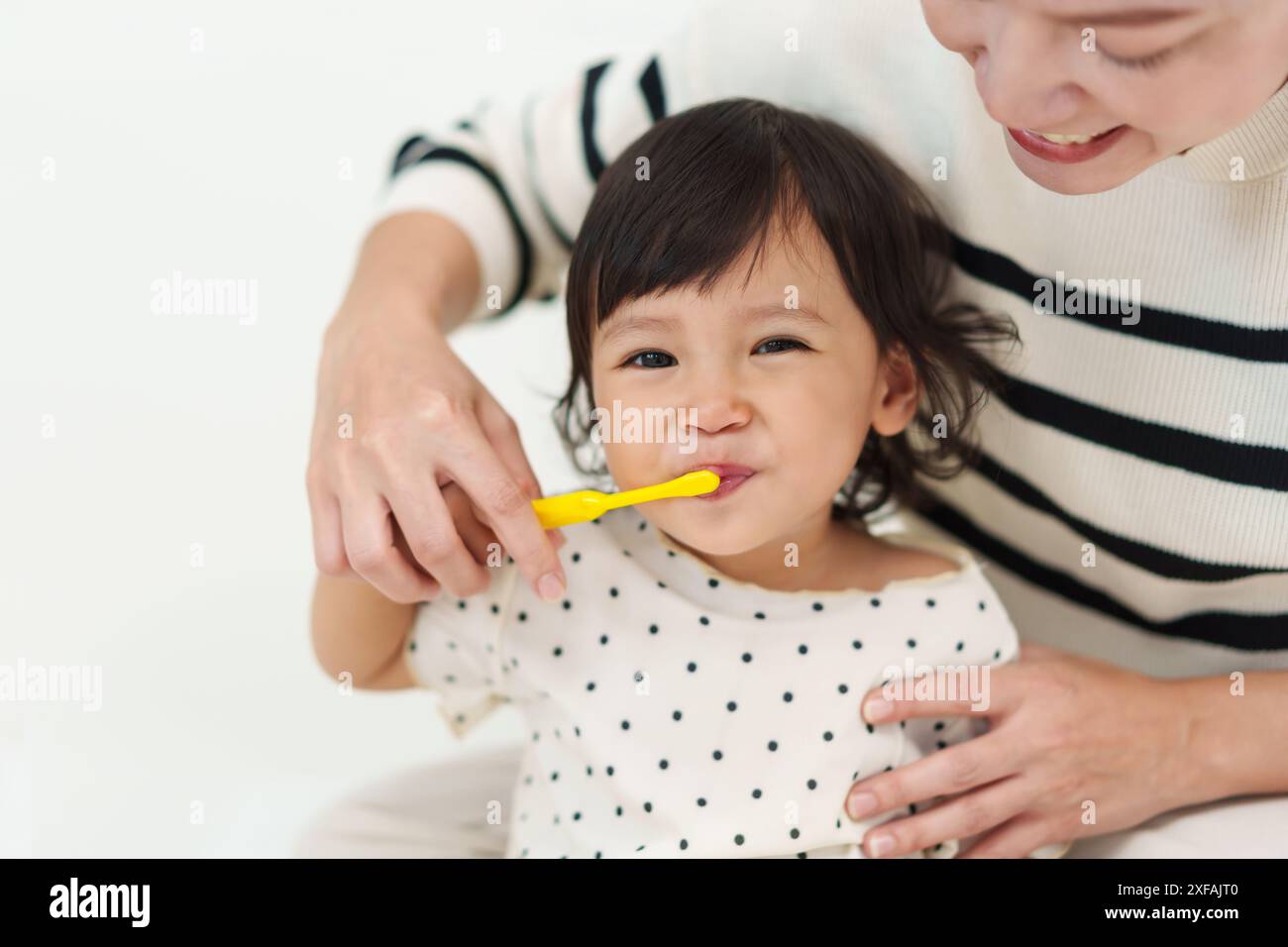 mother brushing her little daughters teeth. happy baby with tooth brush ...