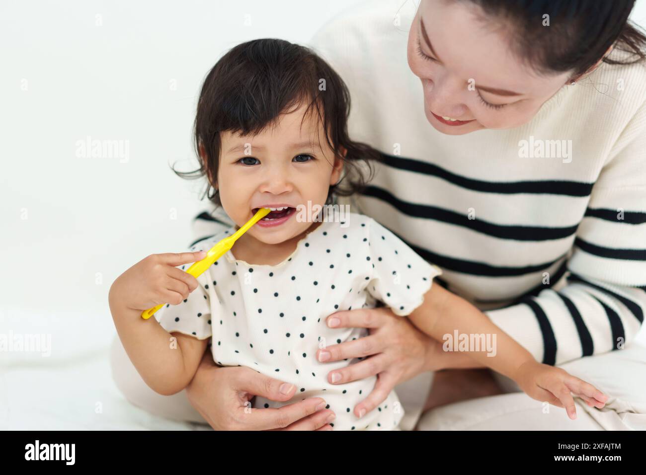 mother brushing her little daughters teeth. happy baby with tooth brush ...