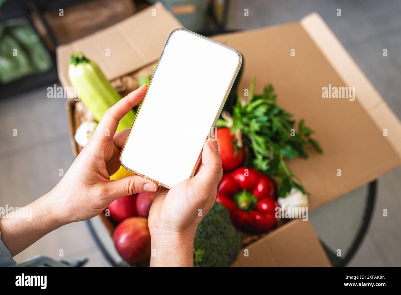 Mockup blank screen of smart phone in female hands above the box with ...