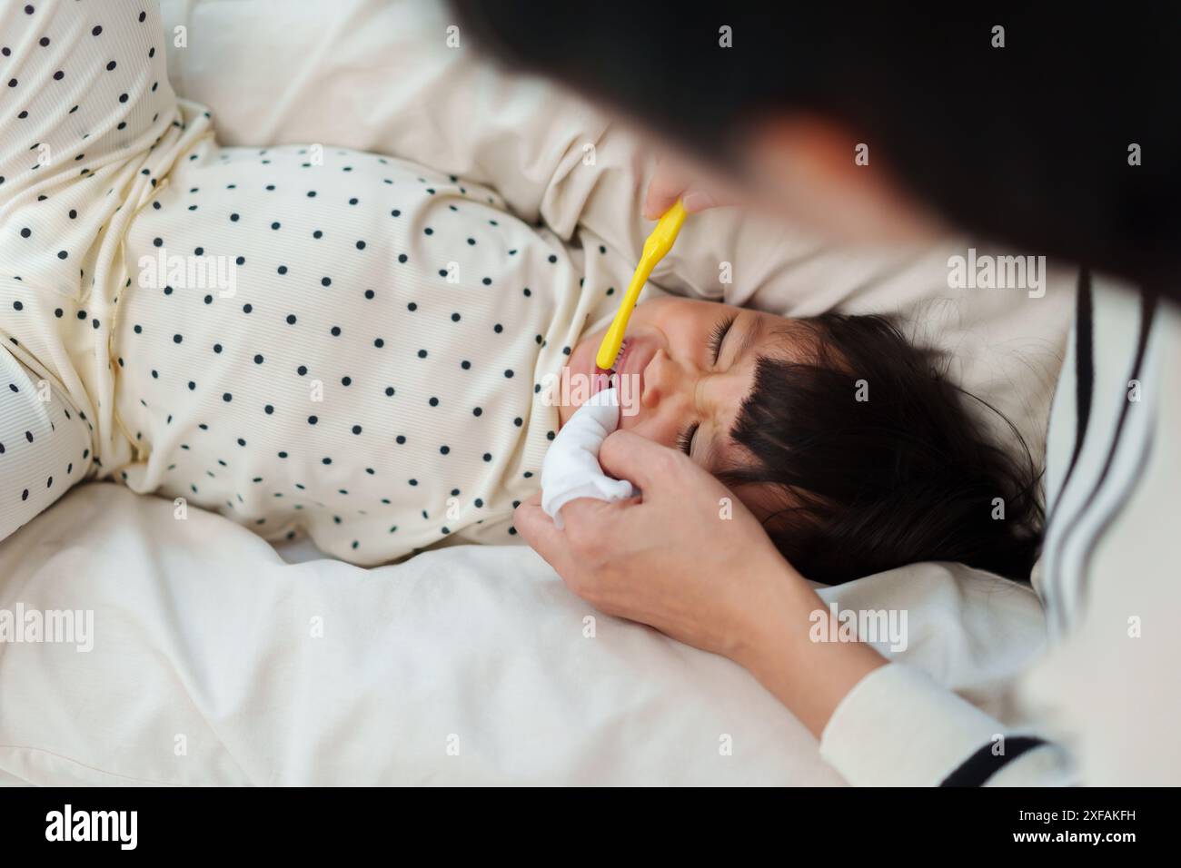 mother brushing her little daughters teeth. crying baby with tooth ...