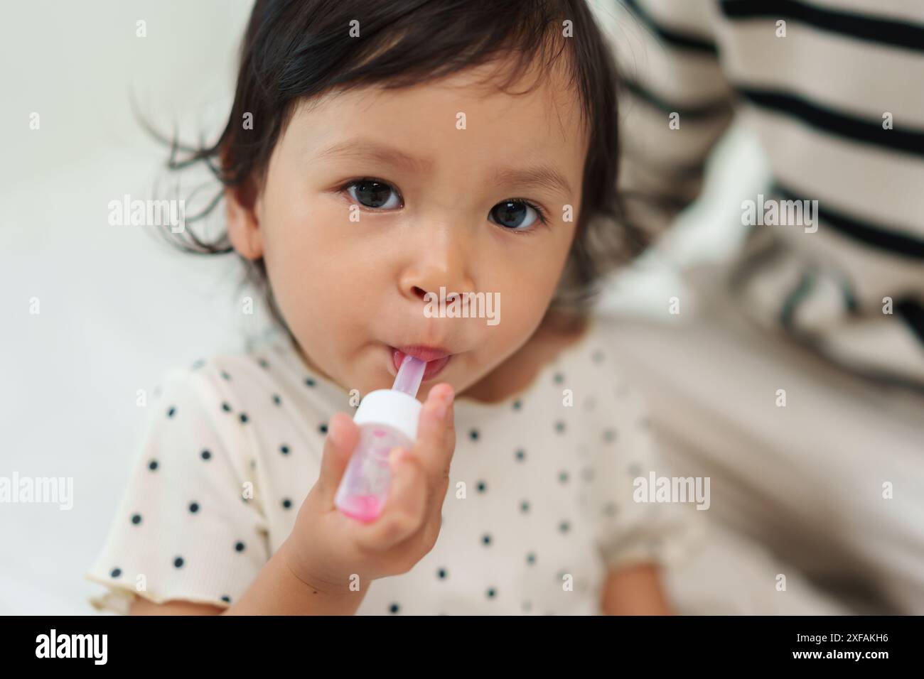 baby girl takes syrup medicine by herself. sick toddler Stock Photo - Alamy