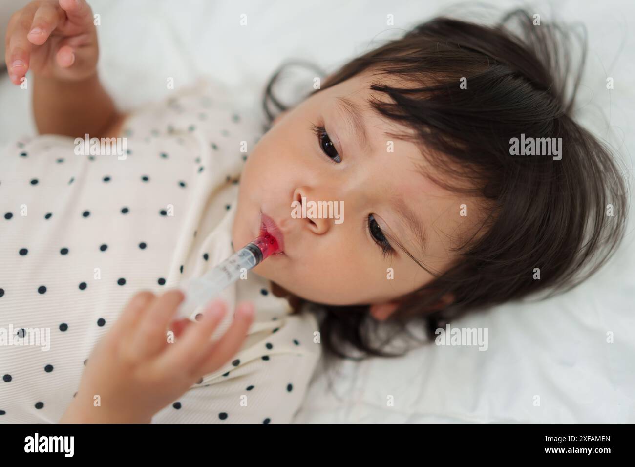 baby girl takes syrup medicine with syringe by herself. sick toddler ...