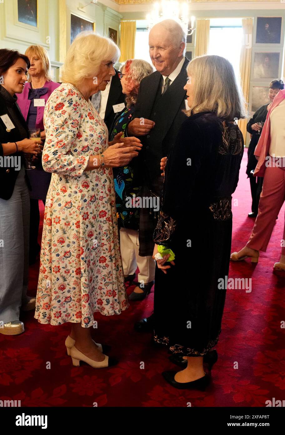 Queen Camilla (left) speaks to Sir Alexander McCall Smith (centre) and ...