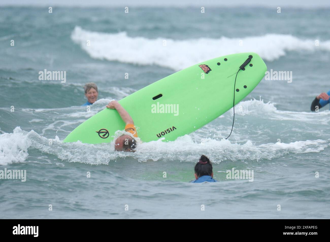 Liberal Democrat leader Sir Ed Davey clings to a surfboard during a ...