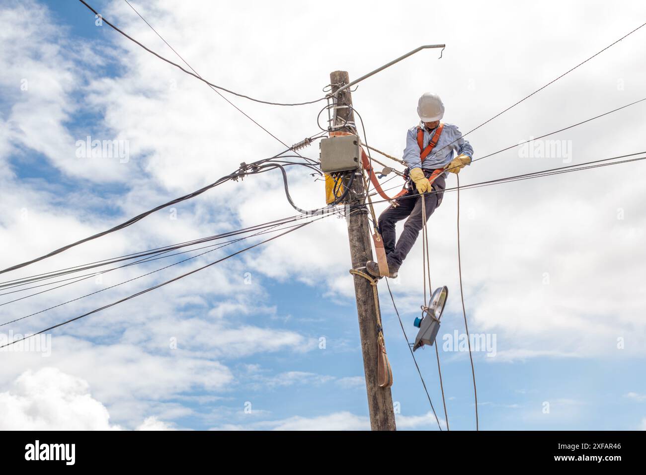 electrician removes old light fixture and unloads it with a rope to ...