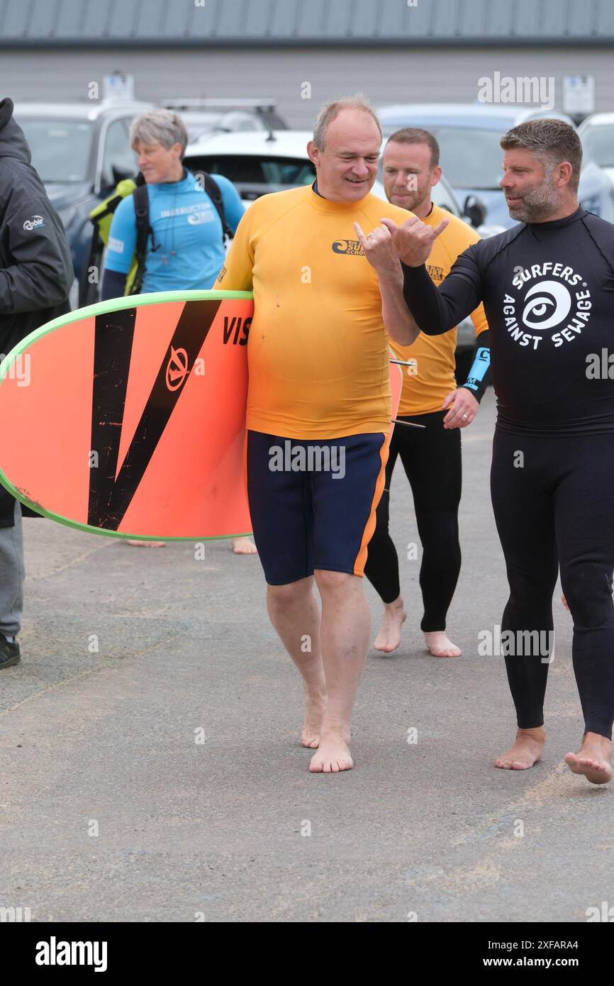 Liberal Democrat leader Sir Ed Davey carries a surfboard during a visit ...