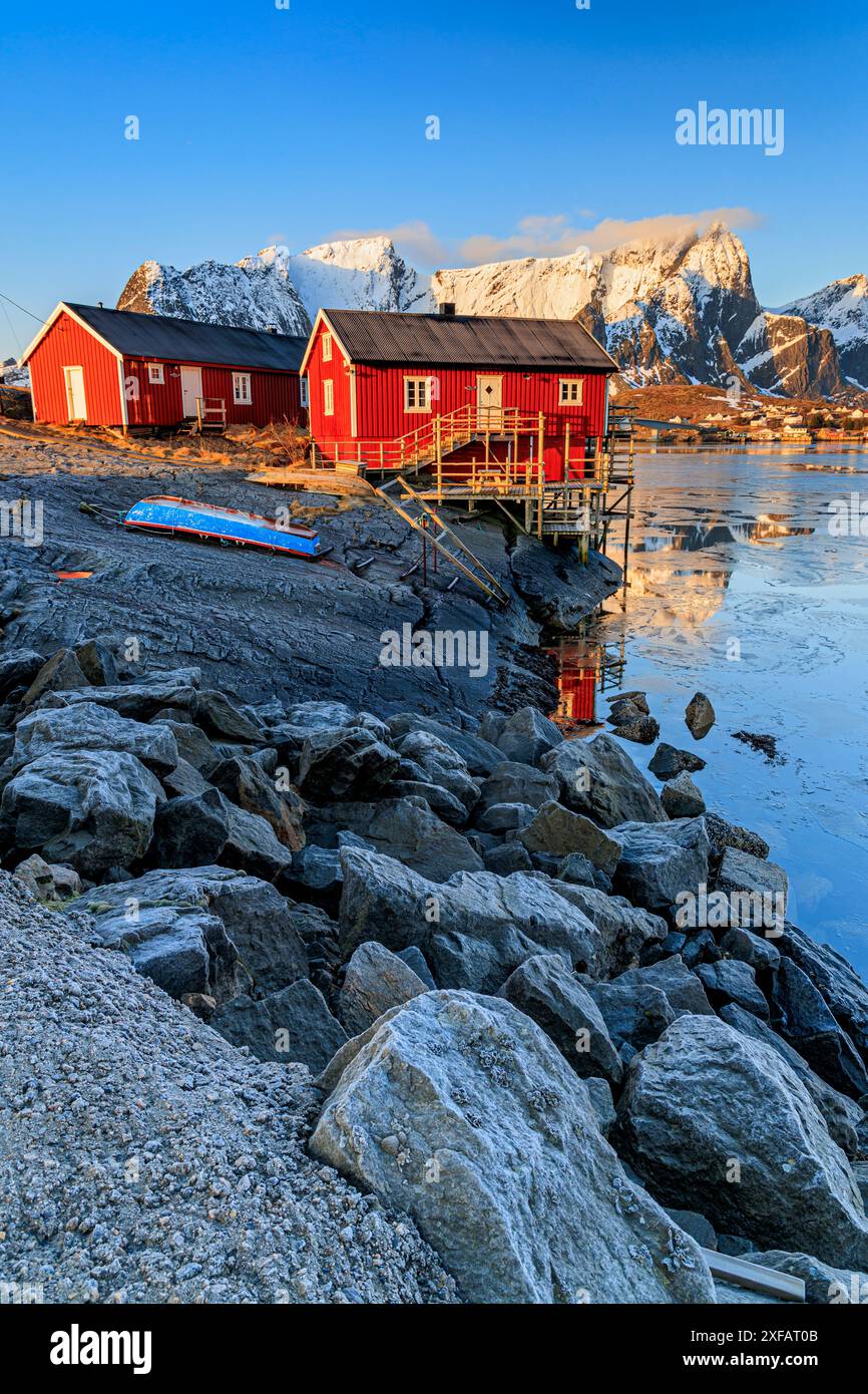 Red houses and village in front of snow covered mountains, fjord ...