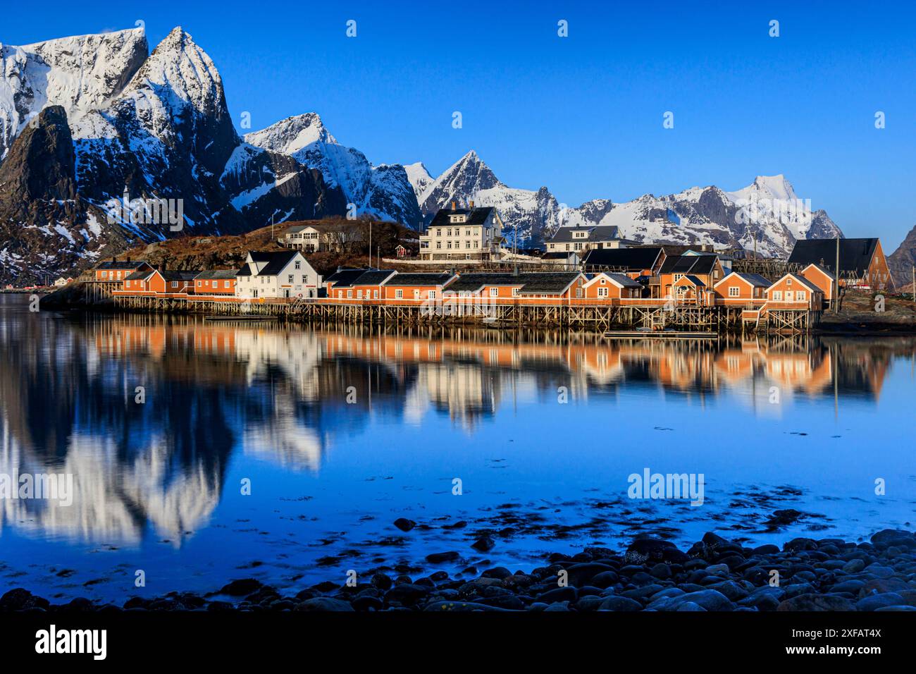 Red houses and village in front of snow covered mountains, fjord ...