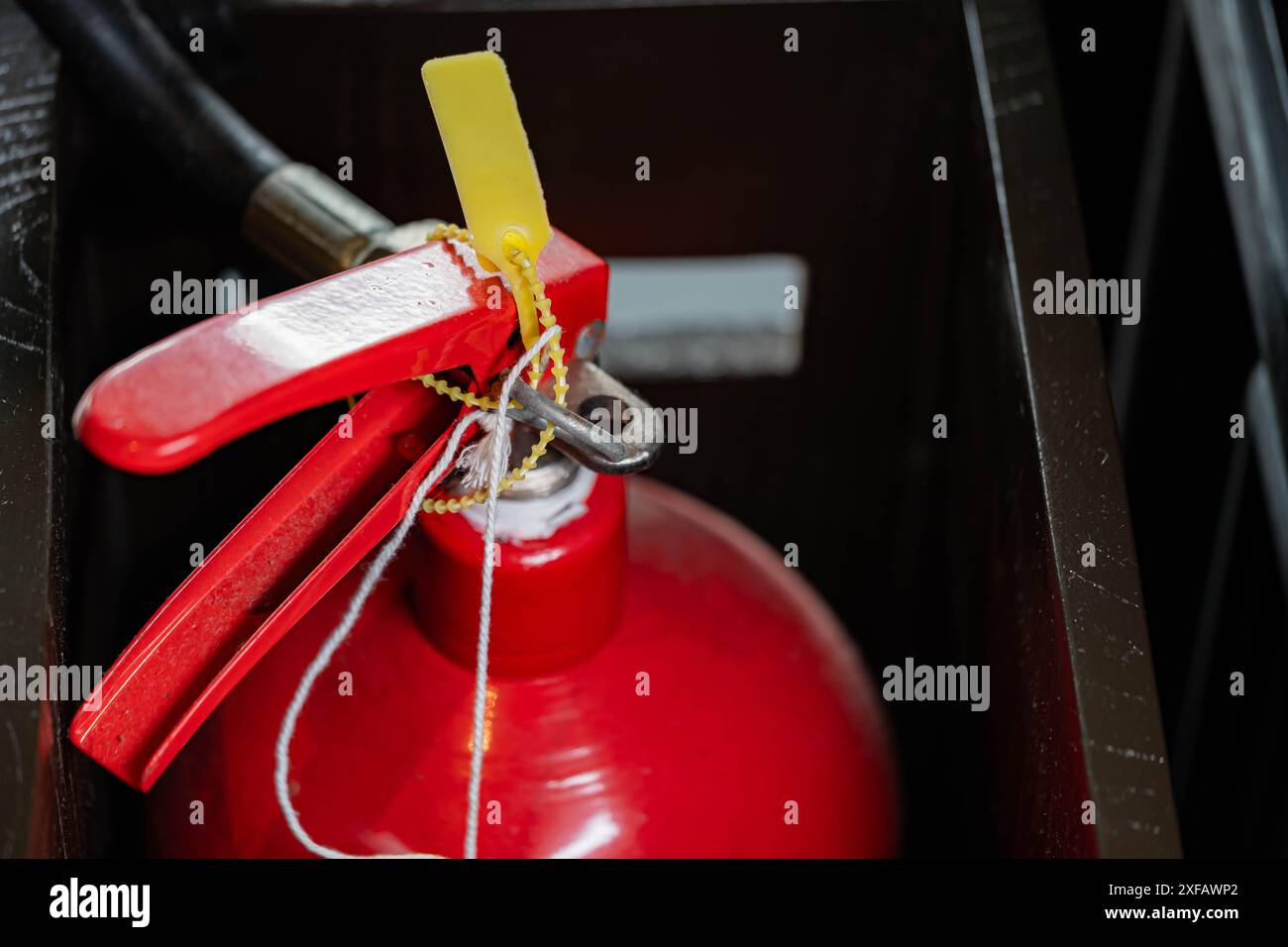 Close-up of a red fire extinguisher with a yellow safety seal and pin ...