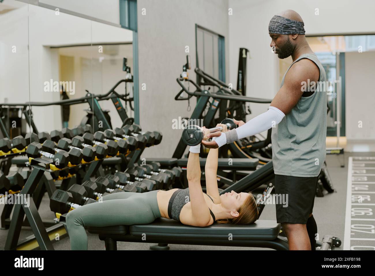 African American coach helping his female client with bulking muscles ...