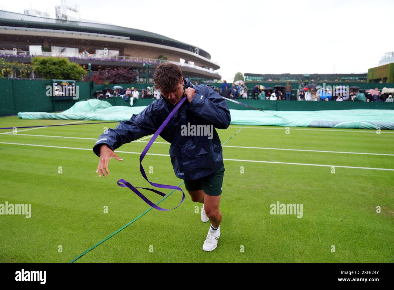Ground staff pull covers over the outside courts as rain stops play on ...