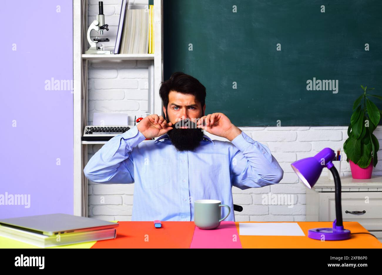 Serious teacher or student sitting at desk in classroom. School teacher ...