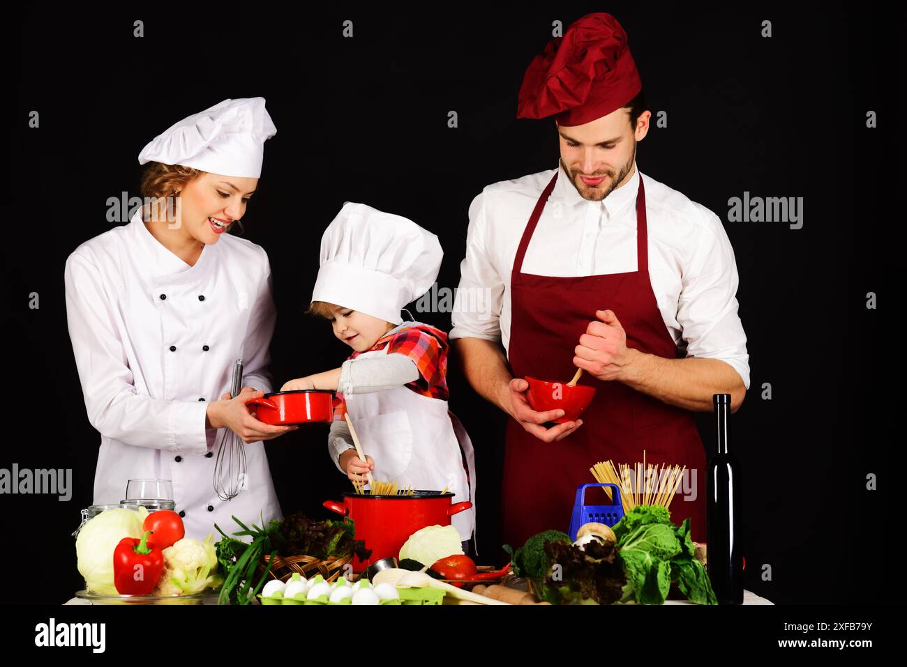Family preparing tasty food in kitchen. Parents teaching little son to ...