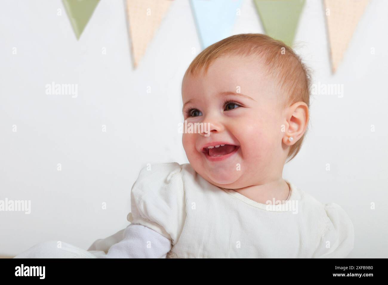 portrait of a cheerful one year baby girl in studio on grey background ...