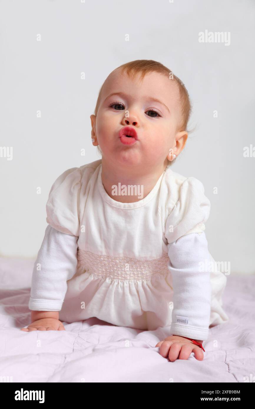 portrait of a cheerful one year baby girl in studio on grey background ...