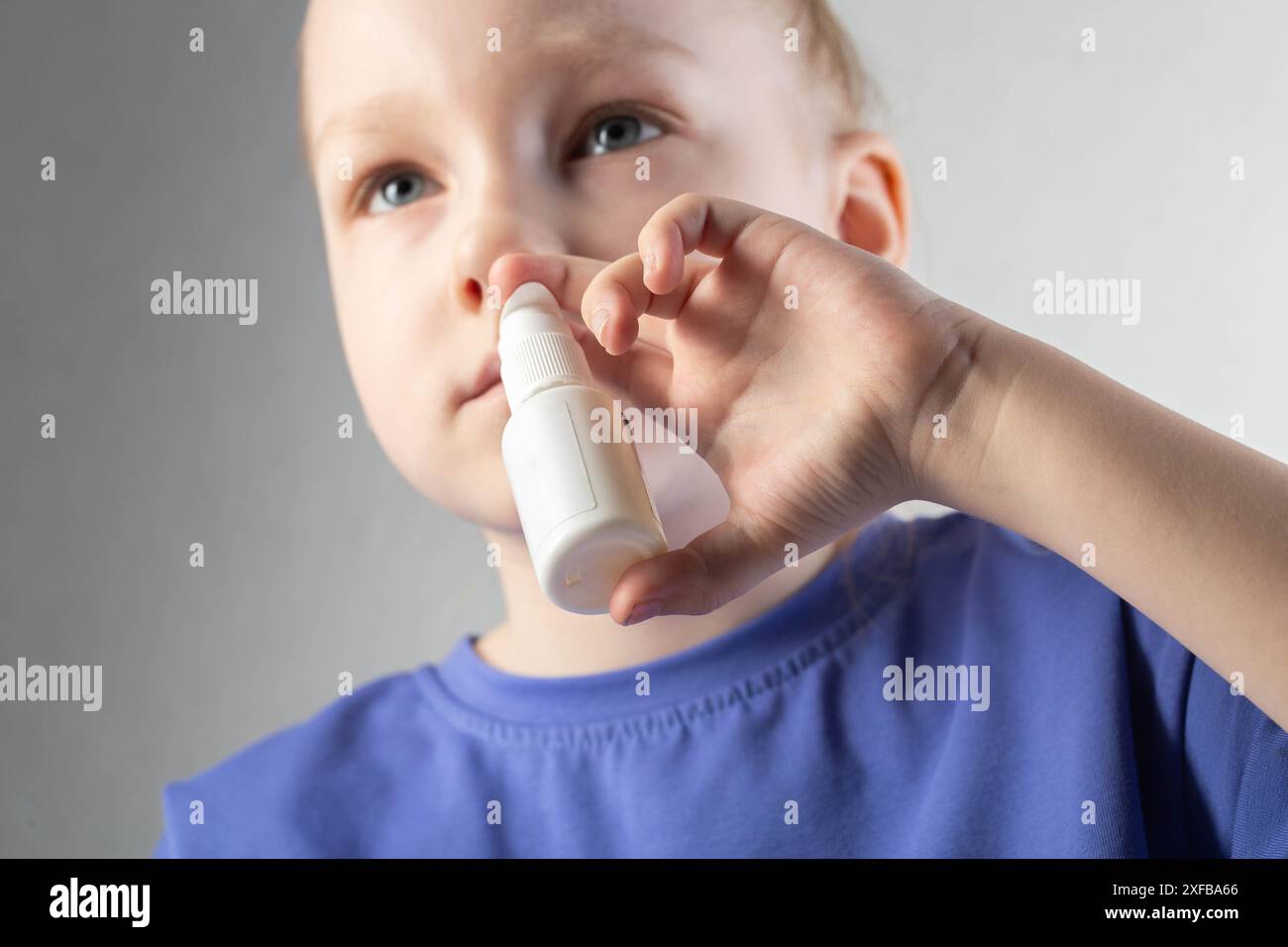 A girl sprays a spray against runny nose and nasal congestion into her ...