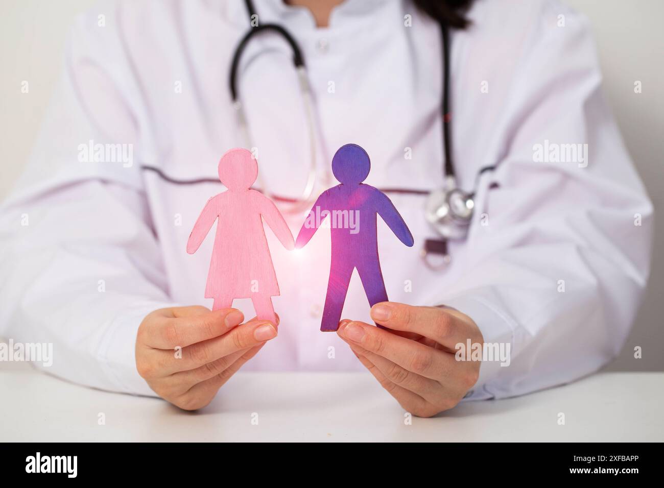 A reproductive doctor holds figurines of a boy and a girl in his hands ...