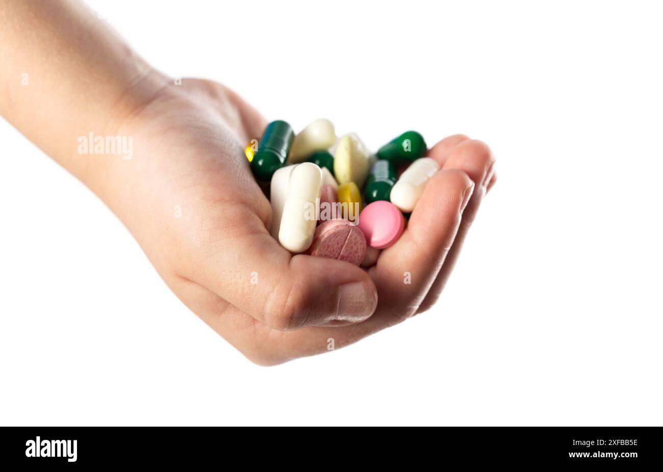 Child's hand with a handful of pills on a white background. The concept ...