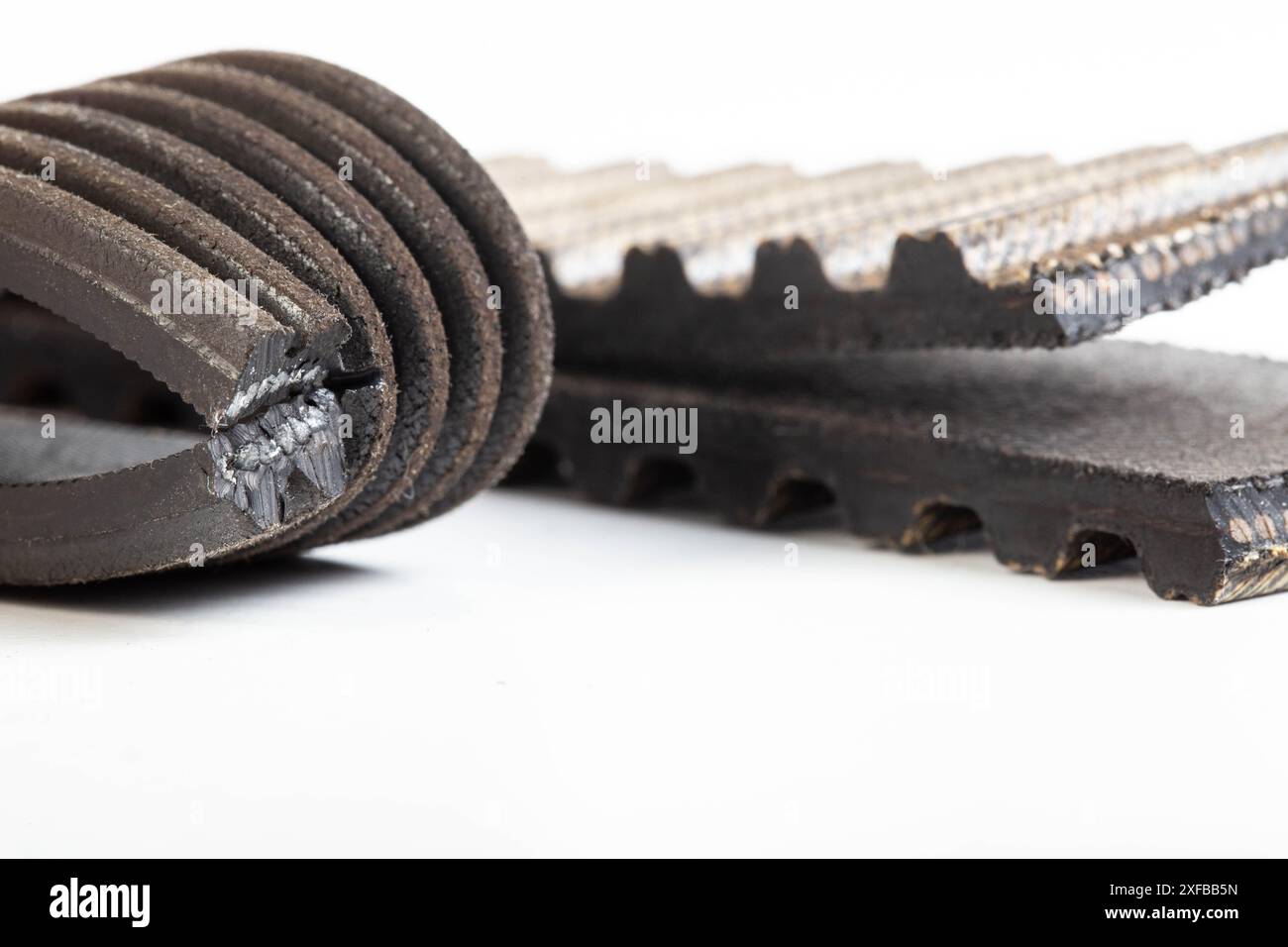 Torn timing belt and generator rivulet belt on a white background ...