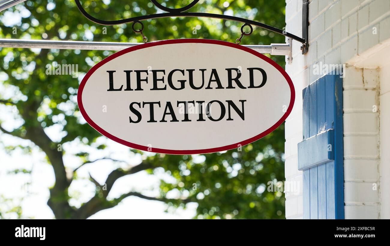Lifeguard station sign hanging outside building with green trees Stock ...
