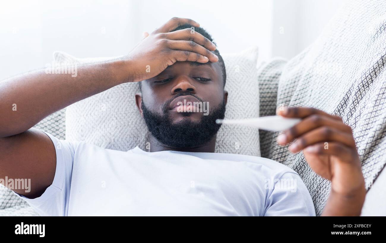 Sick Man Checking Temperature With Thermometer In Bed Stock Photo - Alamy