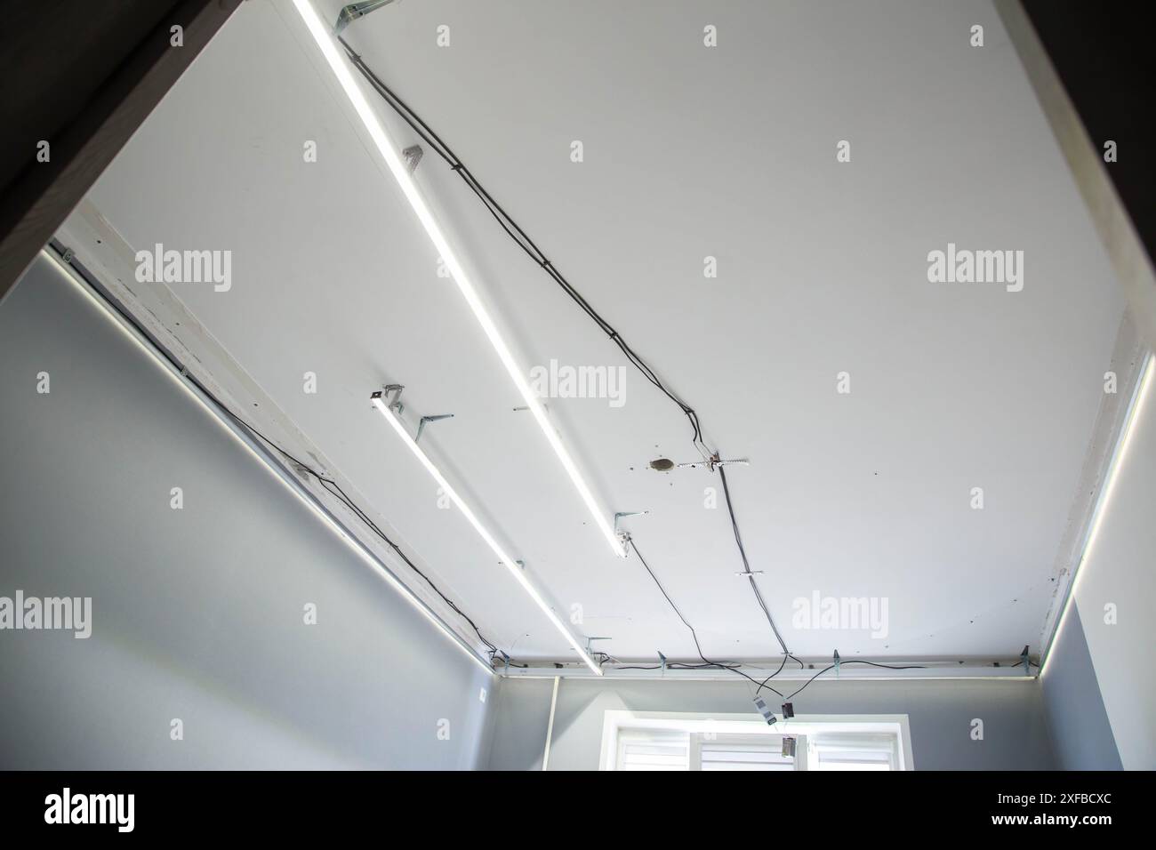 Installation of a suspended modern ceiling with LED light lines in an ...