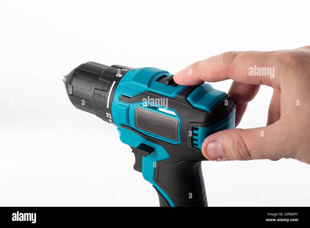 A worker's finger switches the rotation direction switch on a drill ...