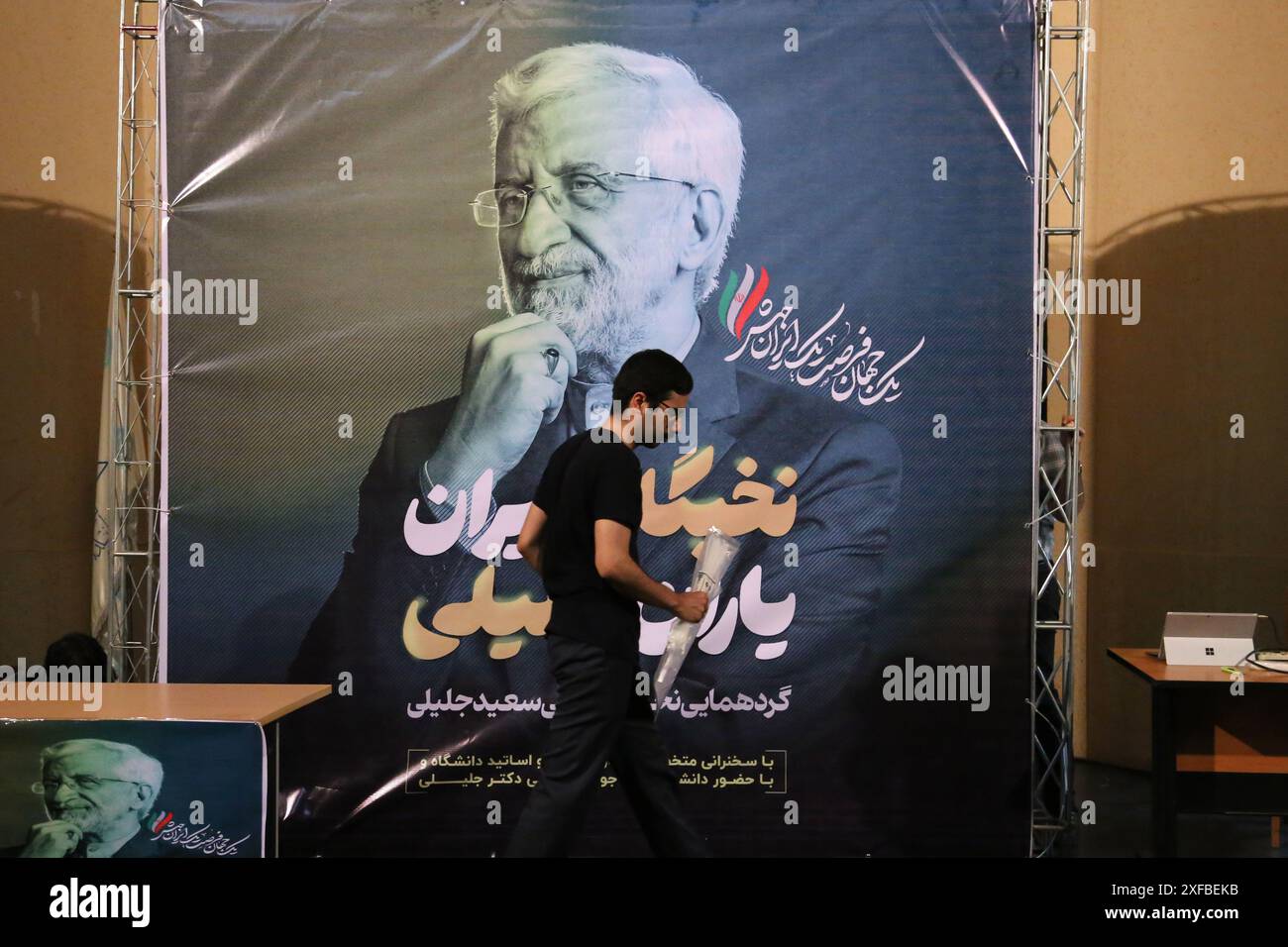 Tehran, Iran. 2nd July, 2024. An Iranian Tehran University student walks past a huge election ...