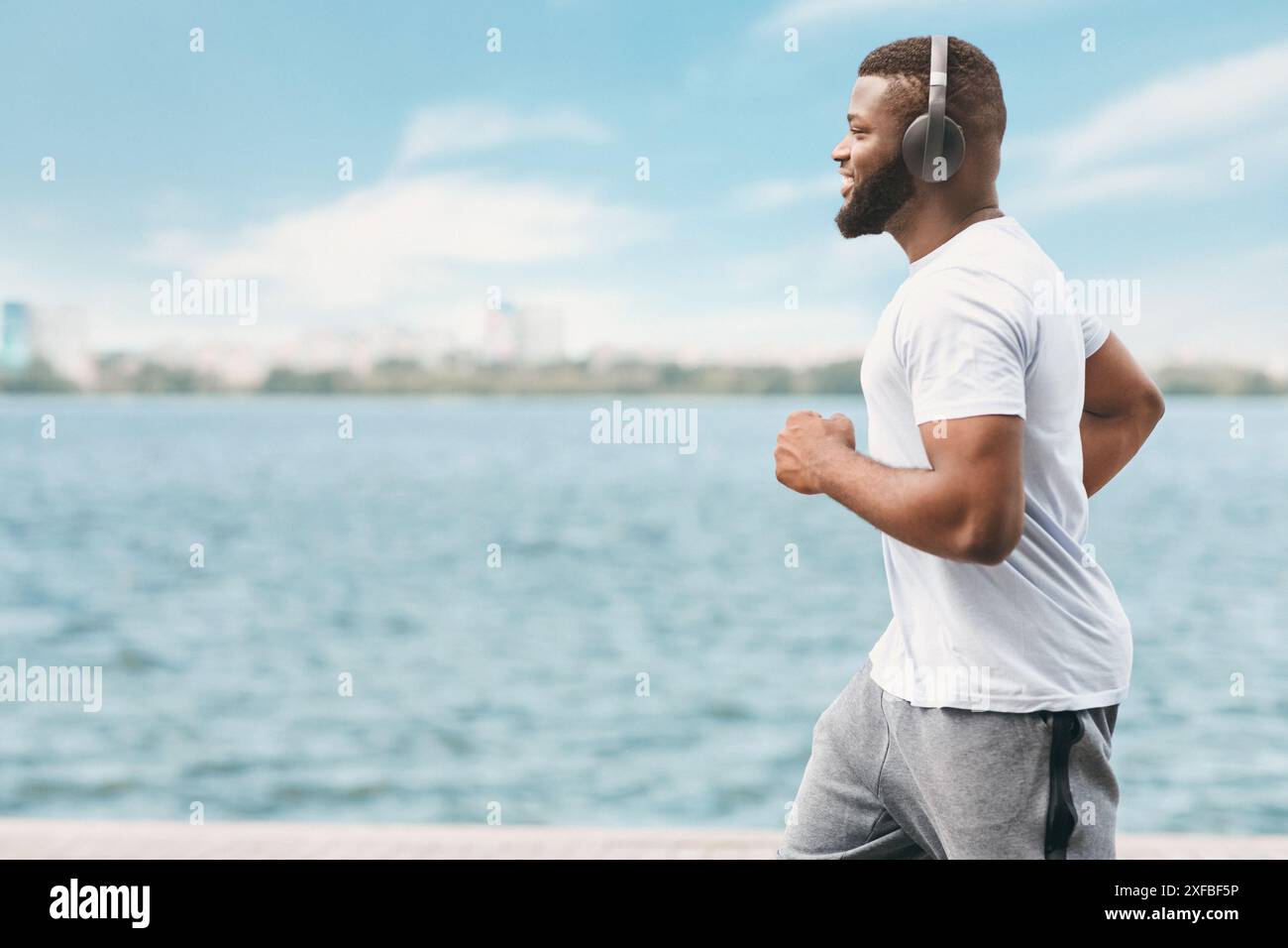 Smiling Black Man Jogging Outside Along River Bank Stock Photo - Alamy