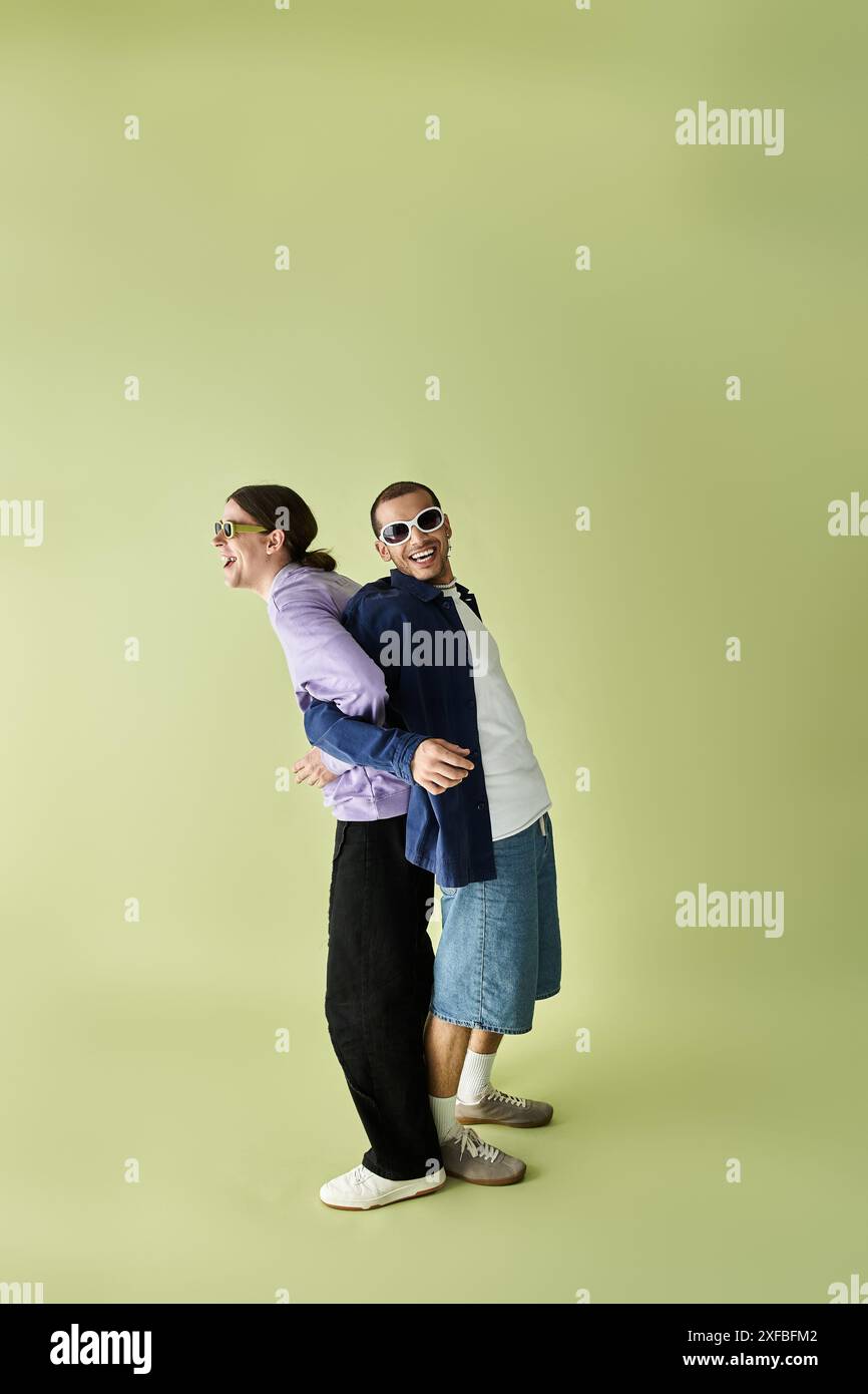 Two men stand side by side in front of a green backdrop, posing ...