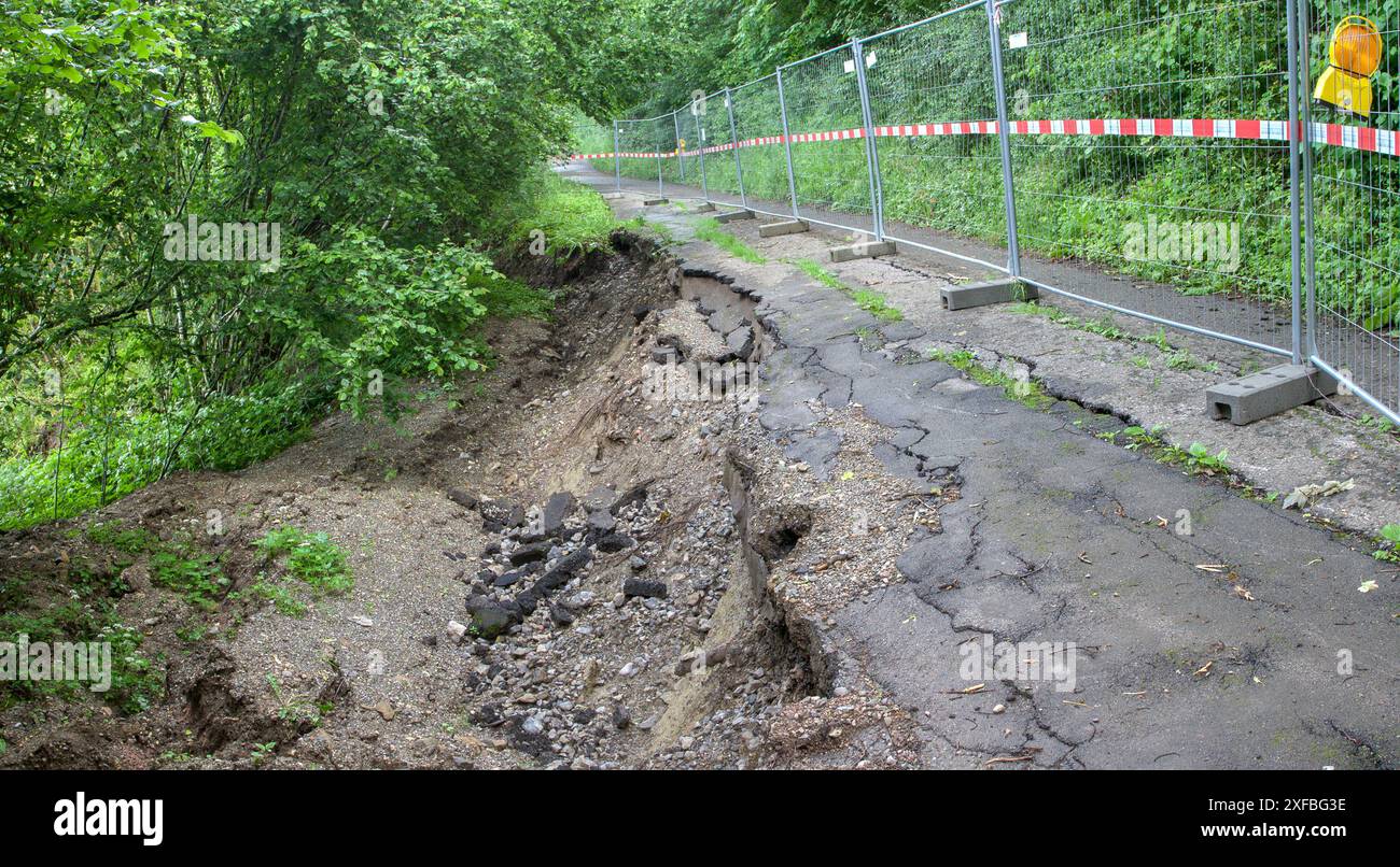 After heavy rain, a small road is blocked off with a construction fence ...