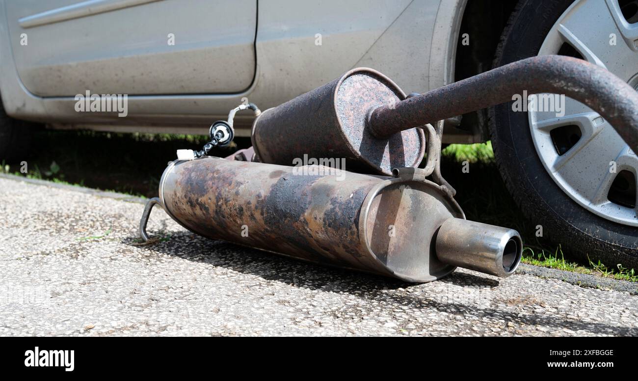 Broken exhaust and muffler of a car, rusted silencer fallen down on the ...