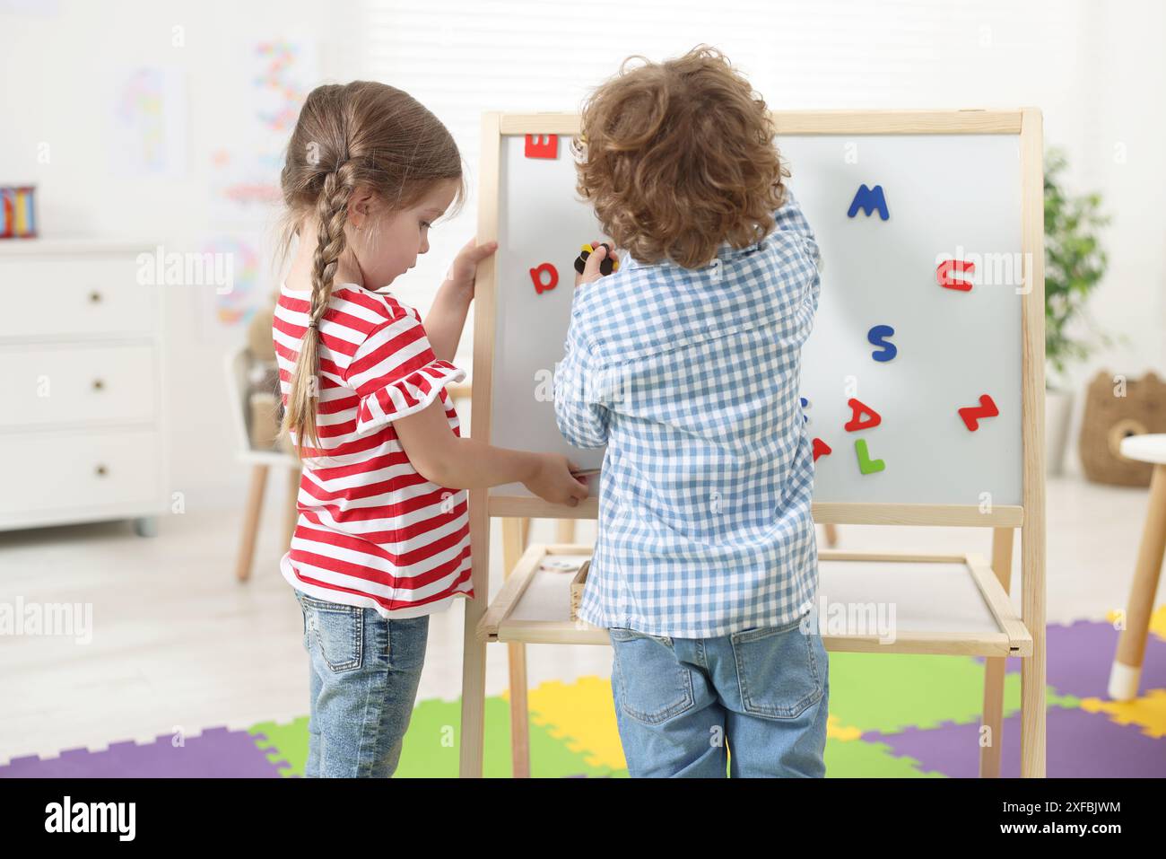 Cute little children learning alphabet with magnetic letters on board ...