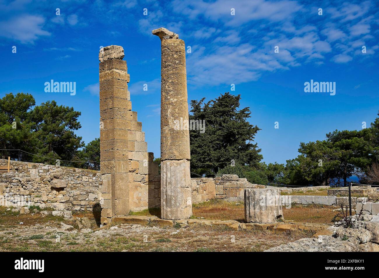 Two well-preserved ancient columns amidst historical ruins under a bright blue sky, Temple of ...