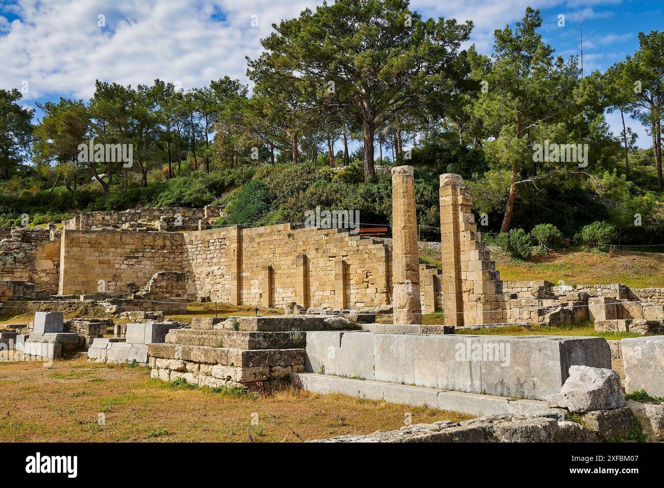 Ancient ruins with columns and stone walls in sunny weather with trees ...
