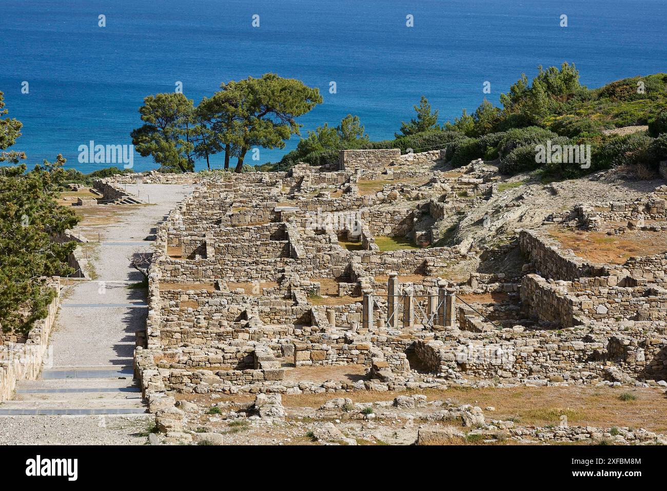 Ancient city ruins with stone structures and trees in front of a sea ...