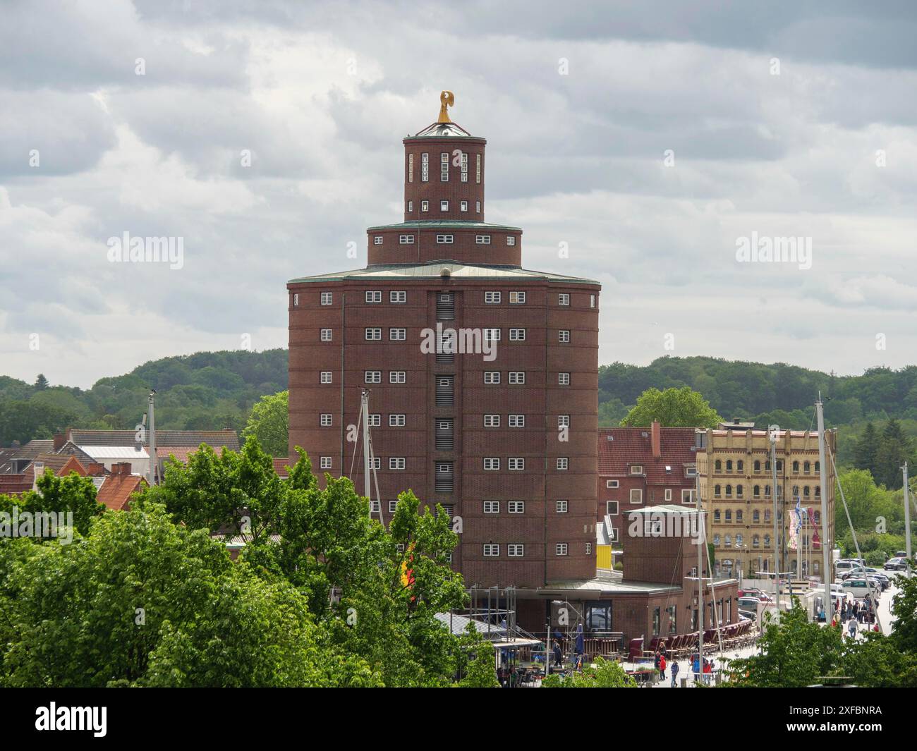 Twelve-storey round brick building against a cloudy sky, surrounded by ...