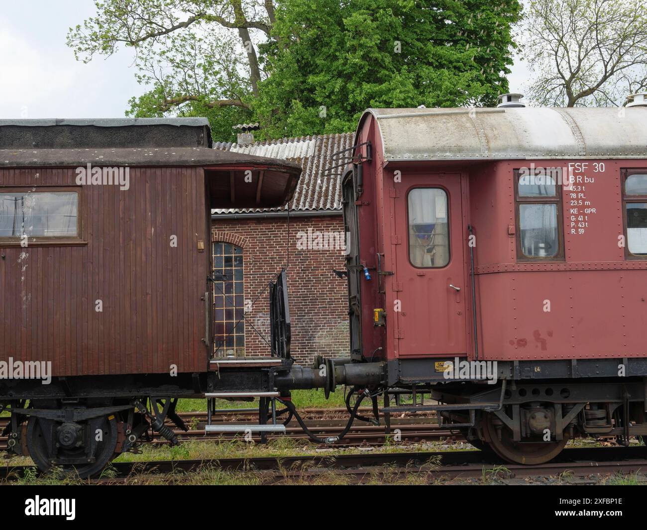 Side view of two old train carriages on railway tracks at a station ...