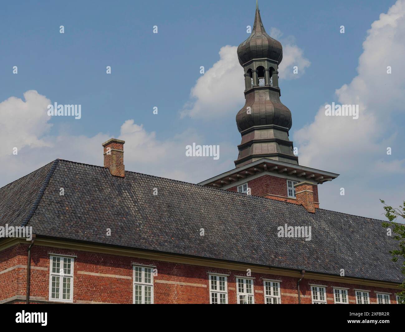 A building with a striking tower, tiled roof and many windows, under a ...