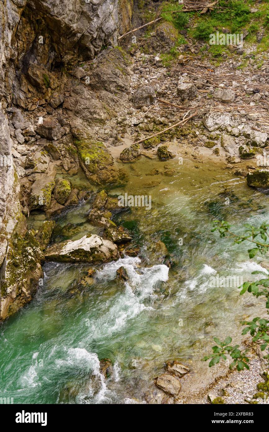 A clear mountain river with green water flows through rocky terrain in ...