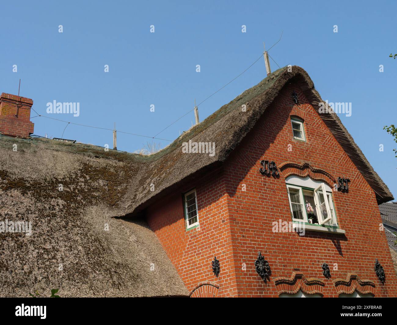 Traditional brick house with thatched roof under a clear sky with white ...