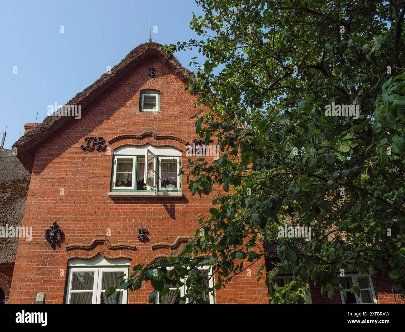 Traditional red brick house with white windows, surrounded by green ...