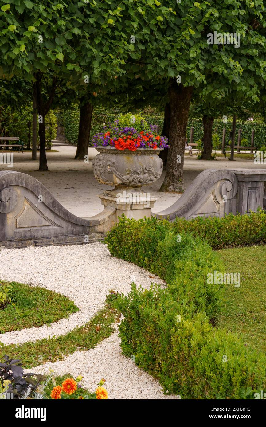 A stylish garden with curved paths, flower arrangements and a stone ...