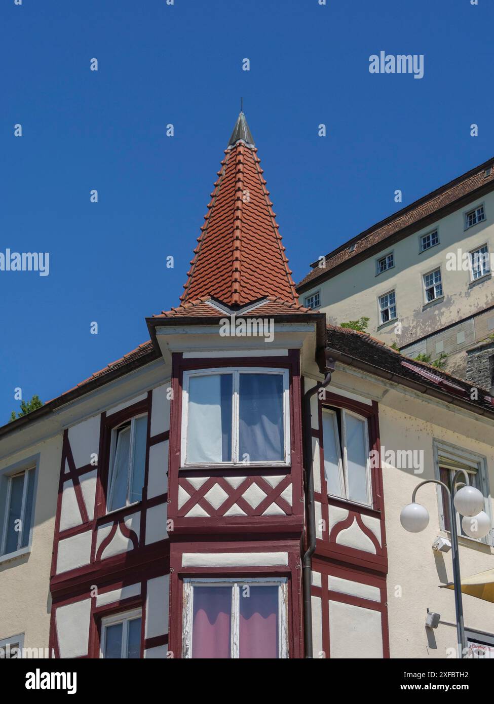 Half-timbered house with pointed tower and red tiled roofs under a ...