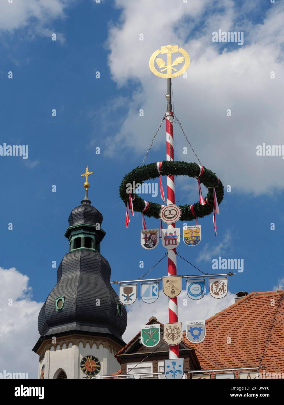Decorated maypole with various coats of arms and flags in front of a ...