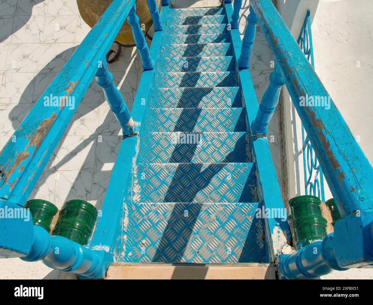 Worn, sky-blue metal staircase with handrail that captures light and ...